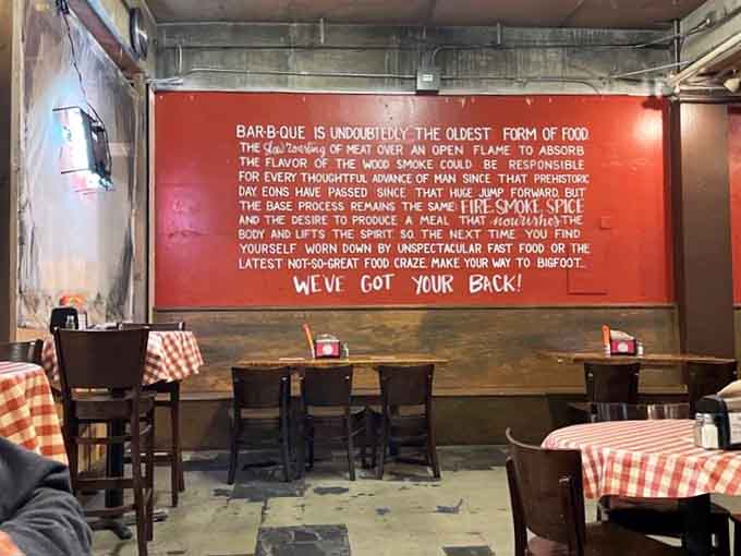 That massive red wall with barbecue philosophy proves this place takes its food seriously and its atmosphere playfully.