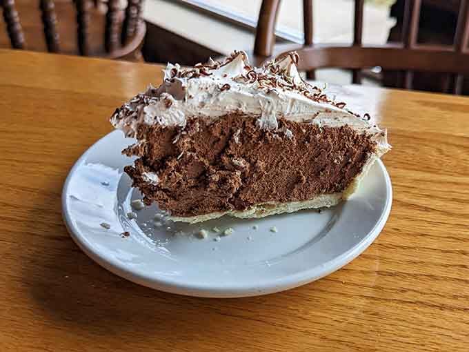 French silk pie towering with whipped cream and chocolate shavings, the kind of slice that requires commitment.