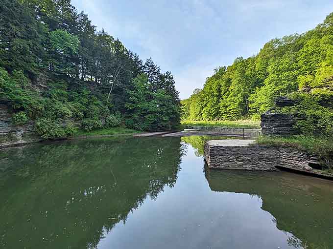Lake Treman's mirror-smooth surface reflects the surrounding forest, creating a scene so peaceful it's almost suspicious.