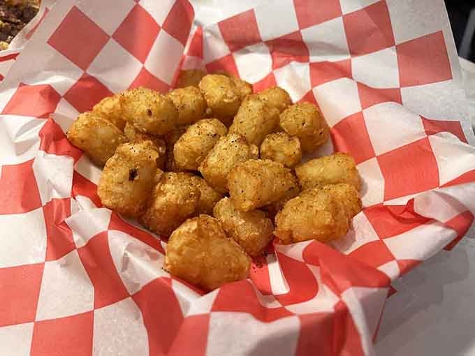 Golden tater tots nestled in checkered paper like little nuggets of crispy, seasoned happiness waiting to disappear fast.