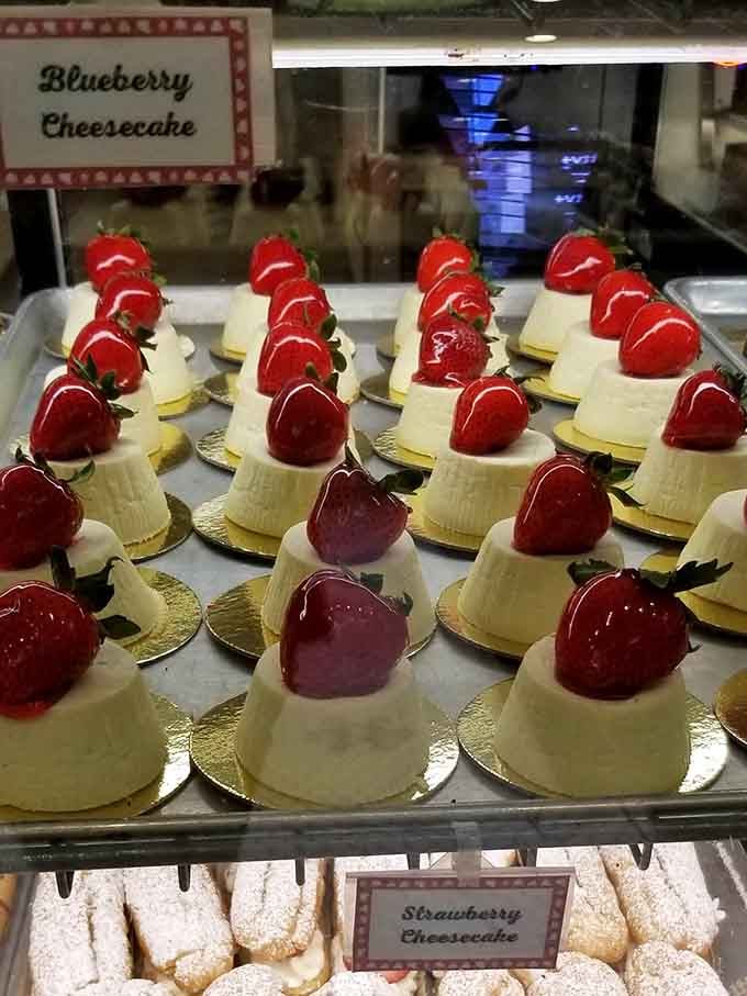Individual cheesecakes topped with glossy strawberries, each one a personal-sized monument to the art of not sharing your dessert.