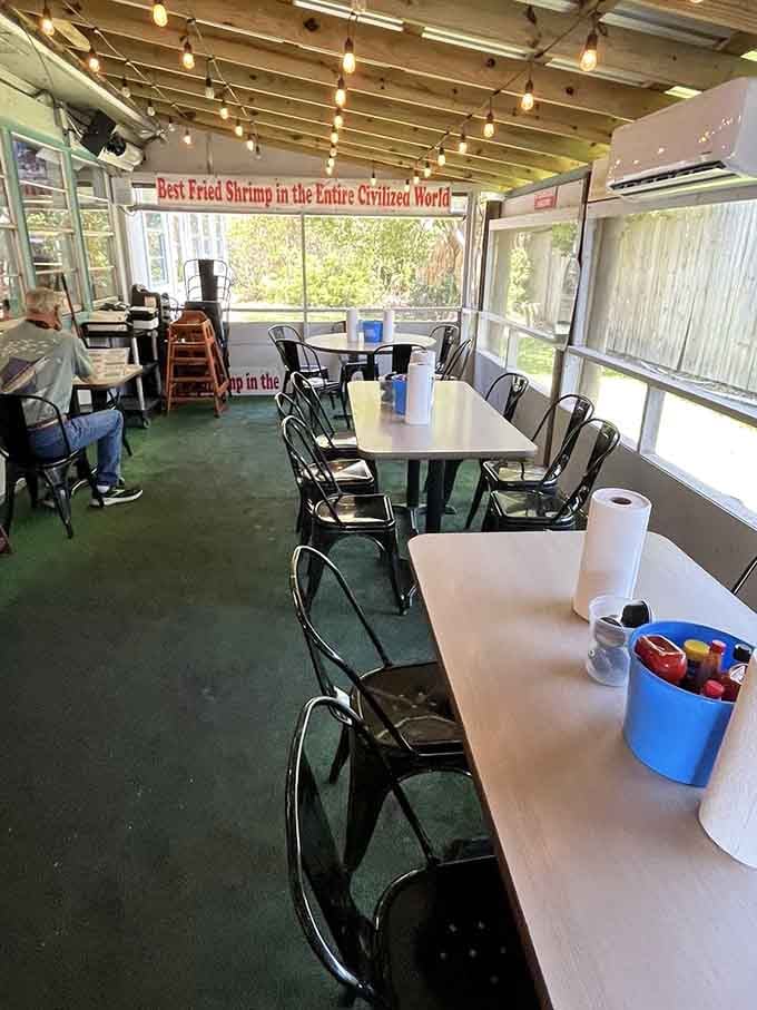 The screened porch seating with string lights overhead turns a casual meal into a breezy coastal experience worth savoring.