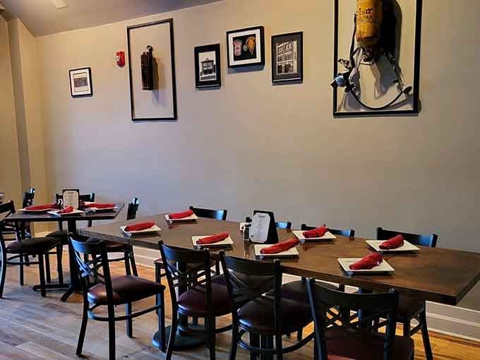 Framed photos line walls above tables set with red napkins, creating understated elegance without the pretension.