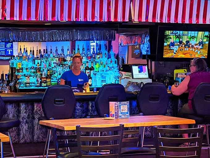 The bar area beckons with backlit bottles and vintage vibes, where conversation flows as smoothly as the drinks.