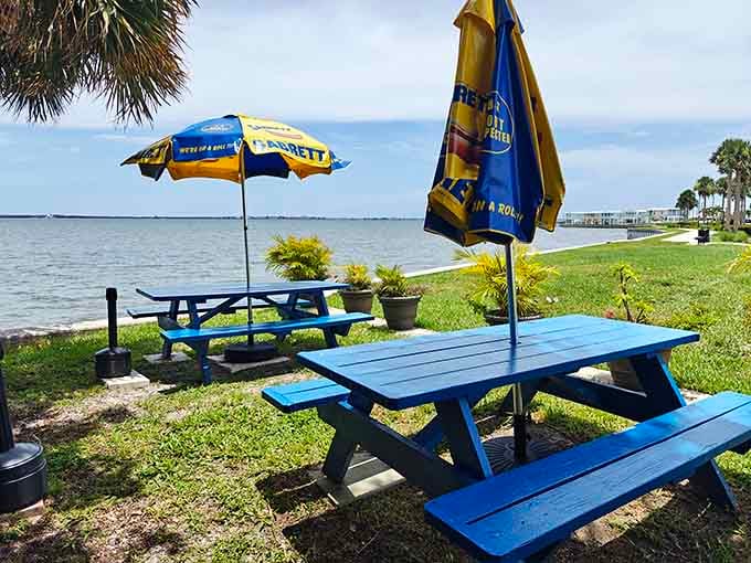 Those bright blue picnic tables with Sabrett umbrellas create the kind of casual waterfront paradise where great meals happen naturally.