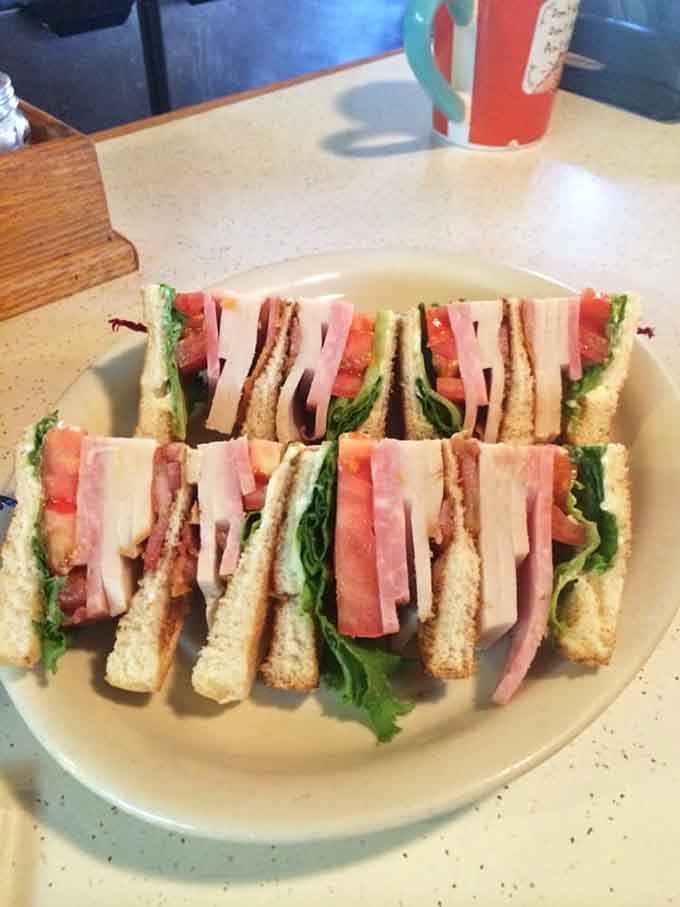 Triple-decker club sandwich architecture that requires engineering skills to eat but tastes absolutely worth the structural challenge.