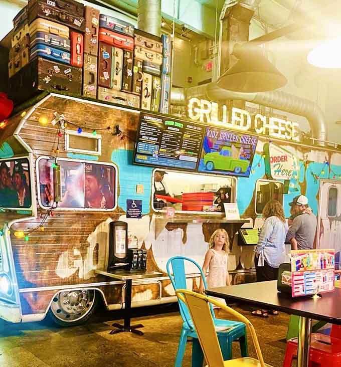 The Grateful Melt counter showcases stacked suitcases overhead, because grilled cheese deserves theatrical presentation and wanderlust dreams.