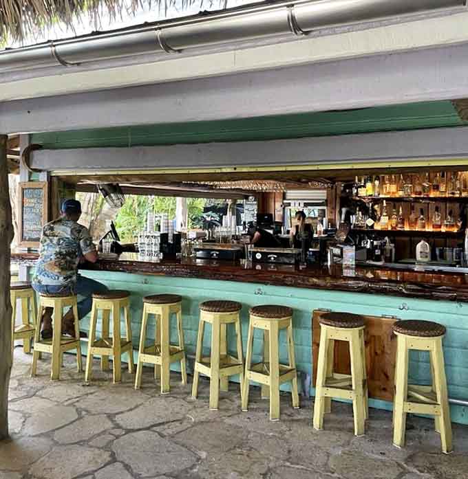 The bar where tropical drinks flow and yellow stools invite you to stay longer than you planned.