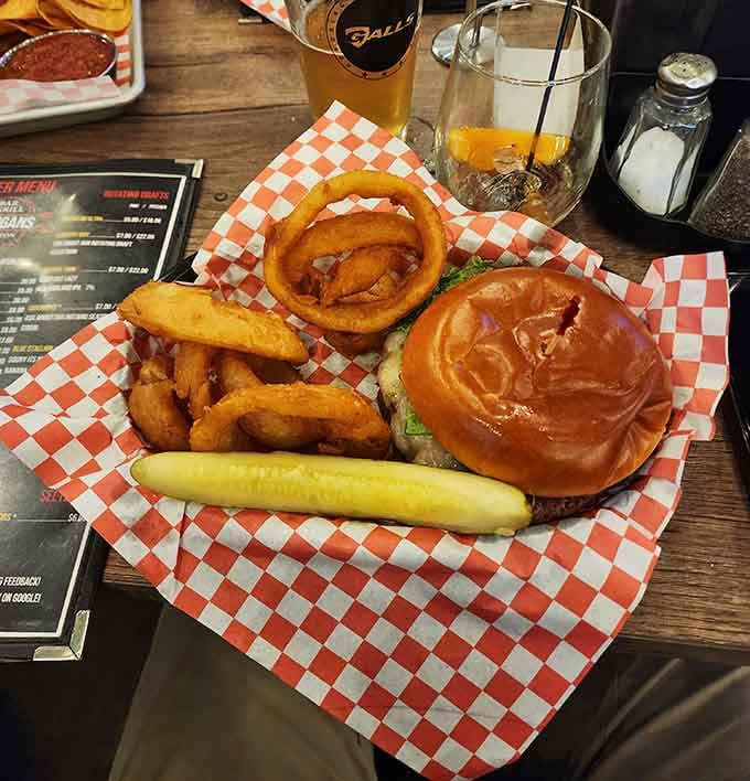 A juicy burger paired with golden onion rings on checkered paper is comfort food poetry written in grease and glory.