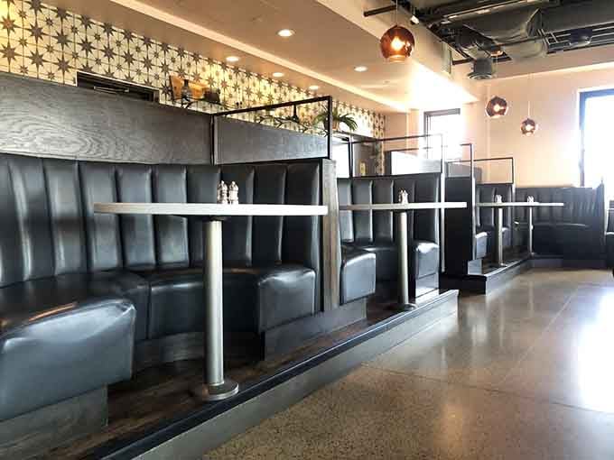 Booth seating with a view of geometric wall patterns creates intimate spaces within the larger theatrical setting.