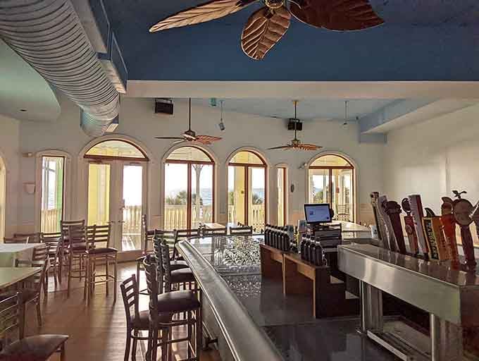 The upstairs bar area features arched windows framing water views and ceiling fans keeping things comfortable year-round in Florida.