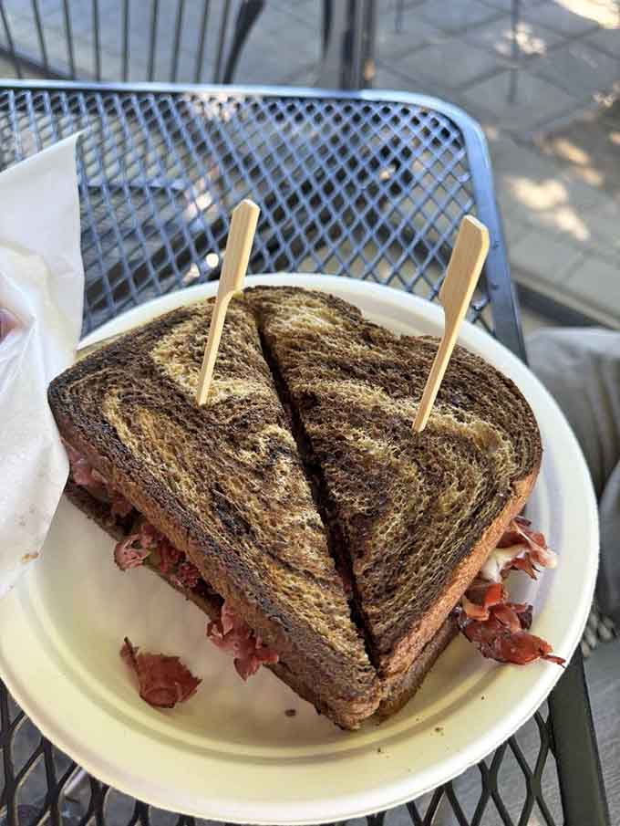 That pastrami sandwich isn't messing around, stacked so high it needs toothpicks just to stay upright and dignified.
