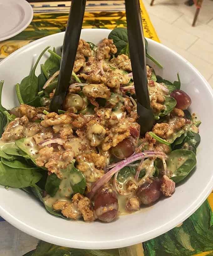 Fresh spinach salad topped with grapes and walnuts offers a lighter option before you dive into pizza heaven.