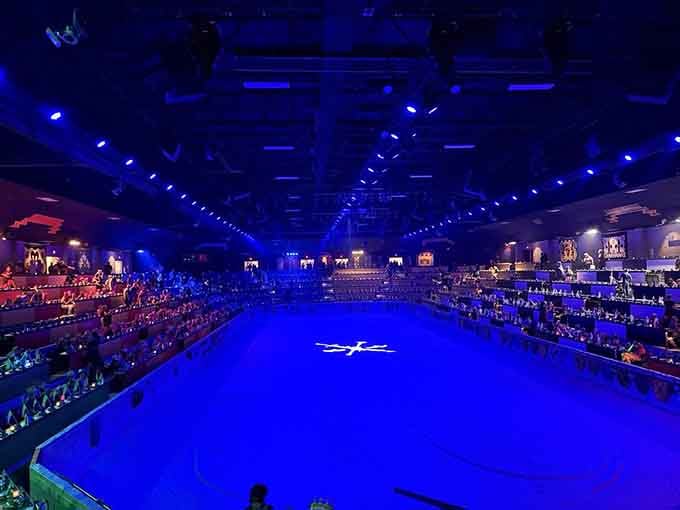 The massive arena glows blue before showtime, anticipation building as a thousand guests await their knights' entrance.