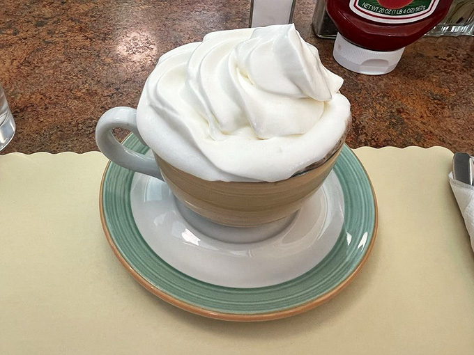 Hot chocolate topped with whipped cream tall enough to require engineering skills to drink successfully.