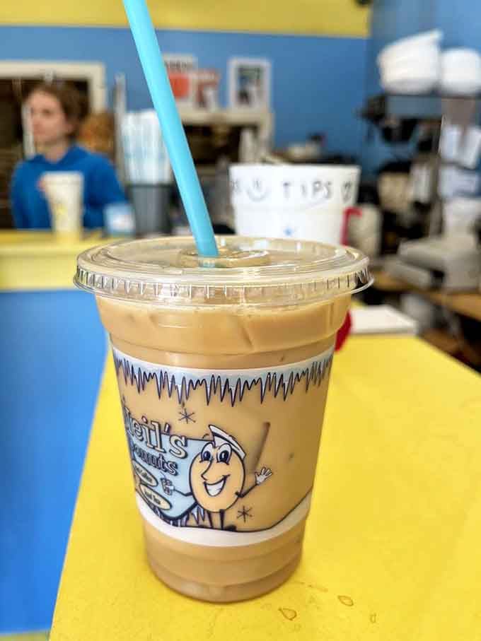 Iced coffee in a cup featuring a smiling donut mascot, because your beverage should always match your mood.