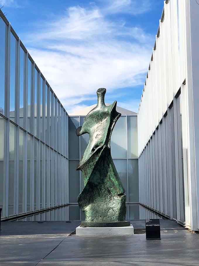 A bronze figure stands guard between glass walls, creating dramatic shadows and proving that placement is everything in art.