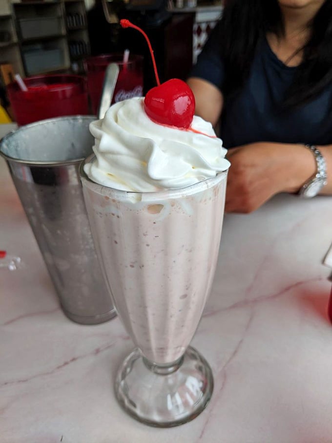 A classic milkshake crowned with whipped cream and a cherry, served in the traditional metal cup for maximum nostalgia.