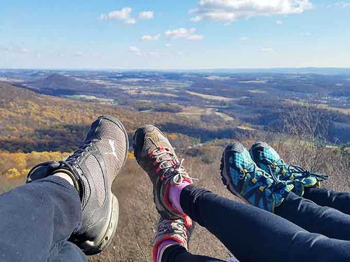Three pairs of well-earned hiking boots dangling over the edge, soaking in views that make sore muscles fade away.