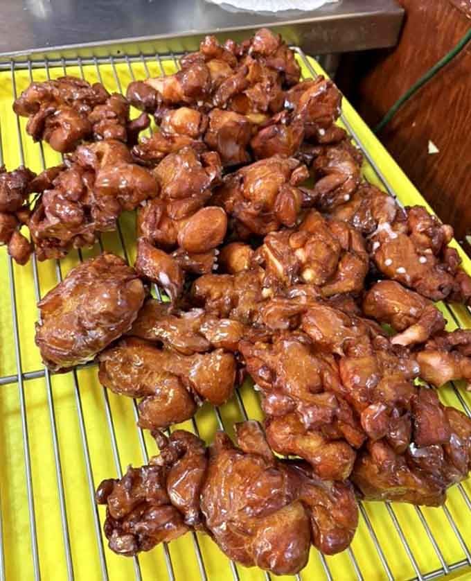 Fresh fritters piled high and glistening with glaze, each one an irregular masterpiece of fried dough perfection.