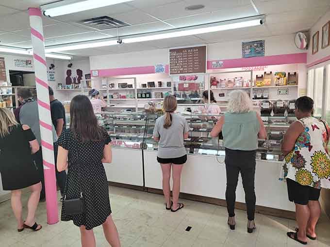 The universal stance of sweet decision-making: customers contemplating life's most delicious dilemmas behind that glass counter.