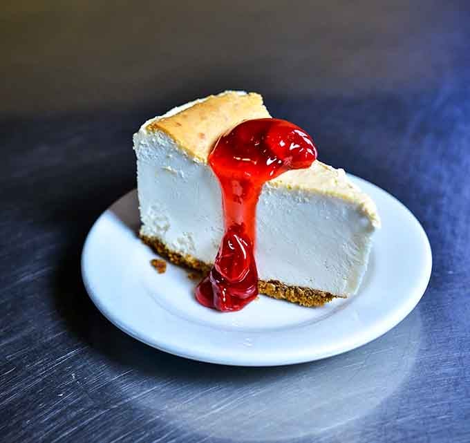 Cheesecake with strawberry sauce that looks like it could solve most of life's minor problems in one bite.