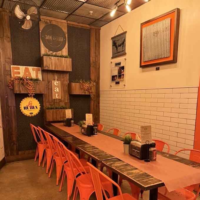 Bright orange chairs against rustic wood prove that barbecue joints can have personality and comfort simultaneously.