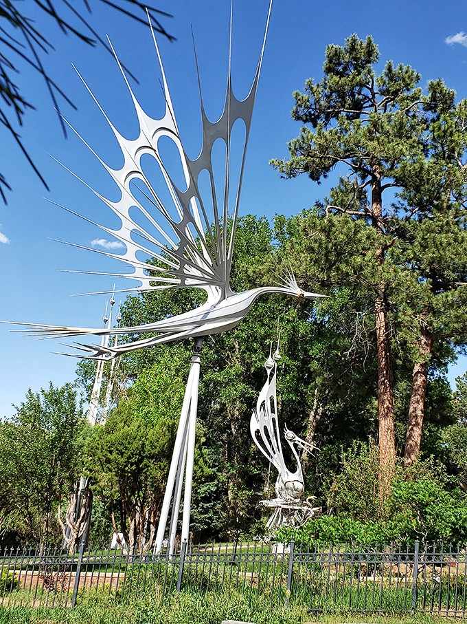 Multiple sculptures create a metallic forest where art grows as tall as the surrounding pines, each piece its own marvel.