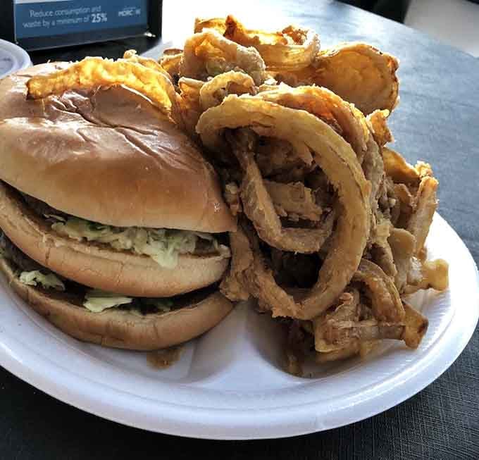 That burger wears its toppings like a crown, surrounded by onion rings that deserve their own fan club membership.