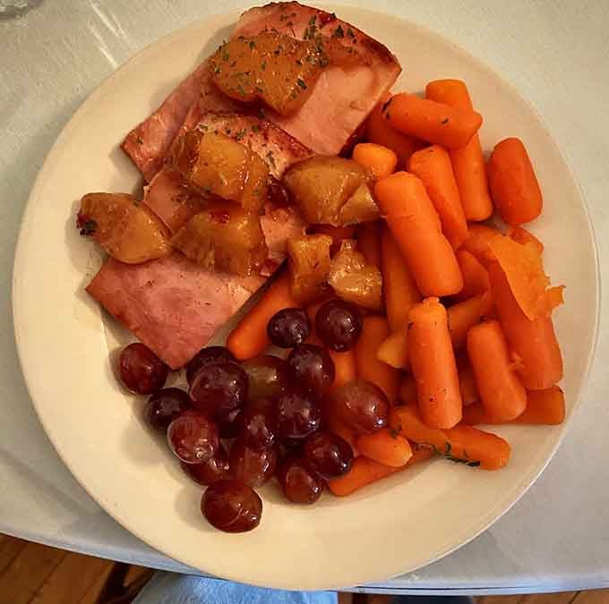 Glazed ham with caramelized pineapple, vibrant carrots, and plump grapes make Sunday supper look like a magazine spread.