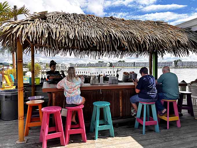 A tiki bar with colorful stools overlooking the water, because sometimes paradise is just a boat ride away.