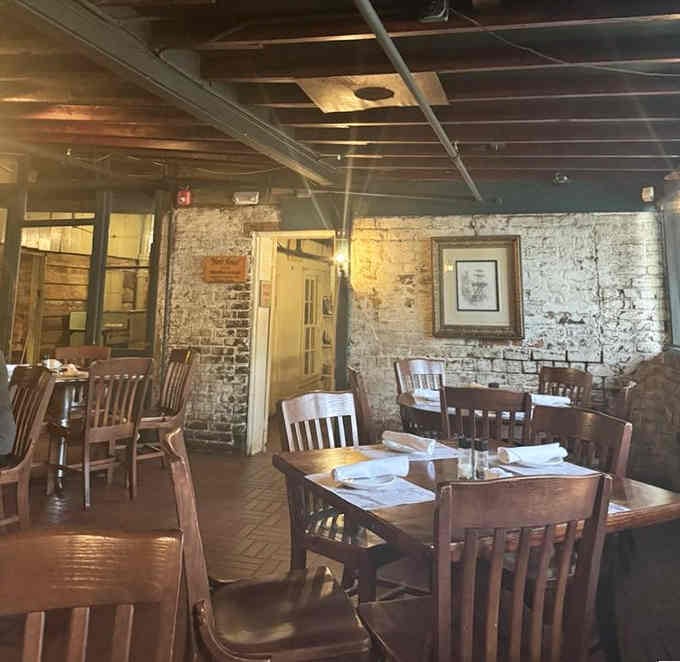 Those aged brick walls and dark ceiling beams frame an intimate dining space that feels authentically timeless, not manufactured nostalgia.