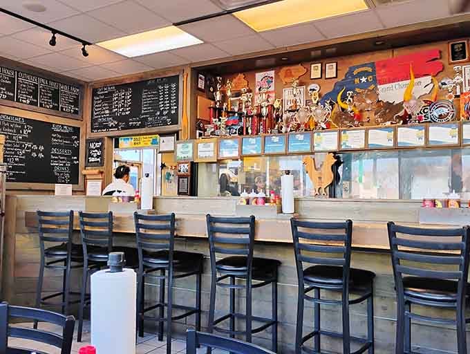 Bar seating beneath a canopy of trophies and awards, where you can eat championship barbecue while admiring the proof.