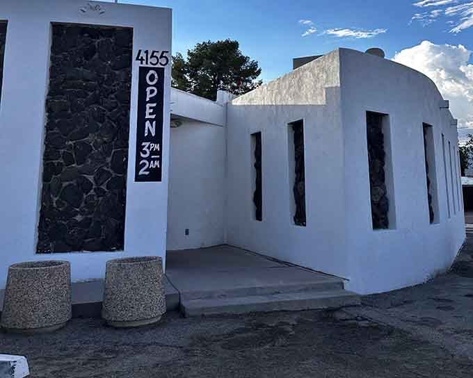 The stark white exterior by day reveals the architectural commitment to that authentic bunker aesthetic we all secretly crave.