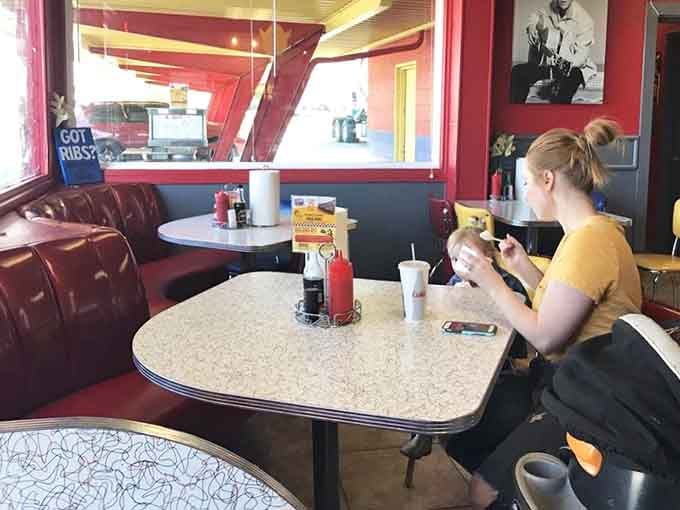 Inside, someone tackles their burger with determination, surrounded by vintage vibes and the promise of satisfaction.