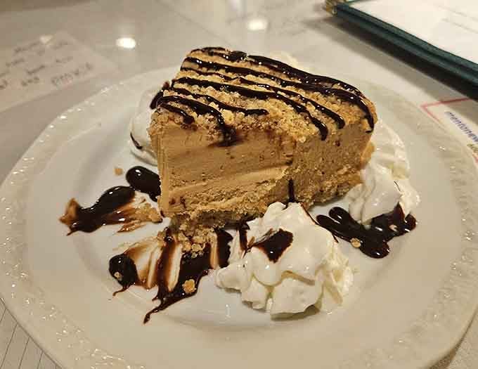 Peanut butter pie drizzled with chocolate, flanked by whipped cream like it's being escorted to dessert royalty.