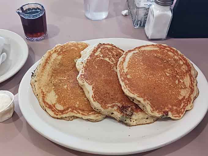 Three golden pancakes that look like they were made by someone who actually understands what breakfast should be.