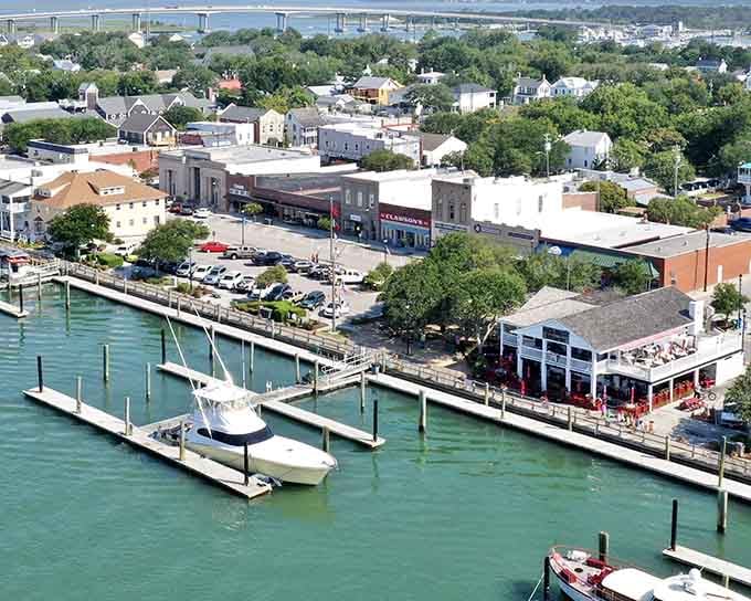 Turquoise harbor waters and sailboats docked along the waterfront evoke Mediterranean coastal villages on lazy summer days.