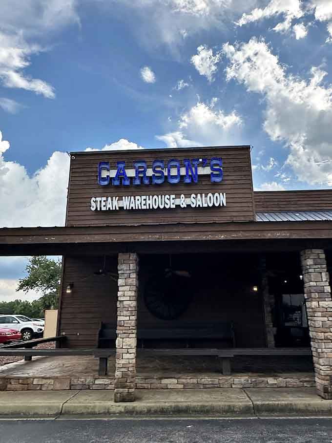 That rustic wooden exterior and stone pillars under dramatic clouds create pure Western saloon vibes with serious steak credentials.