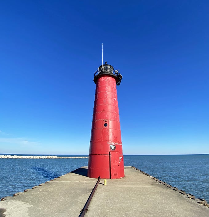 This coral-red tower against blue sky looks like a giant crayon marking the spot where lake meets land perfectly.