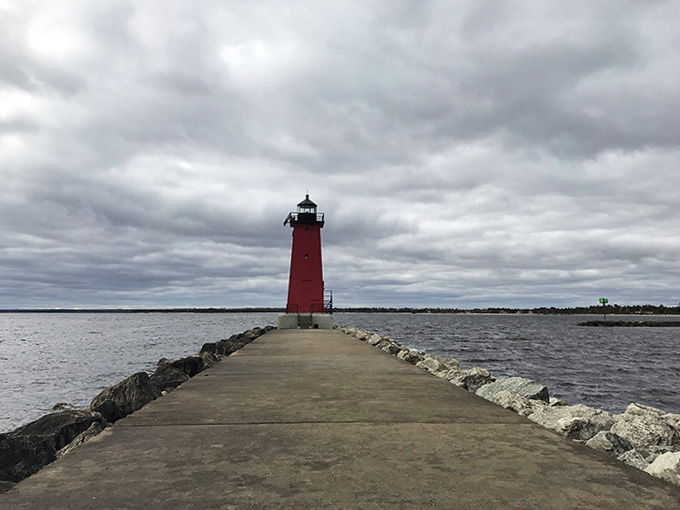Dramatic clouds frame the red tower at the pier's end, nature providing the perfect theatrical backdrop.
