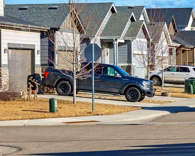 Modern homes stand shoulder to shoulder in neat rows where front lawns meet wide suburban streets.