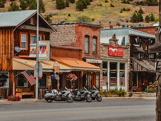 Historic brick buildings line the street where motorcycles rest after winding through mountain roads all morning.