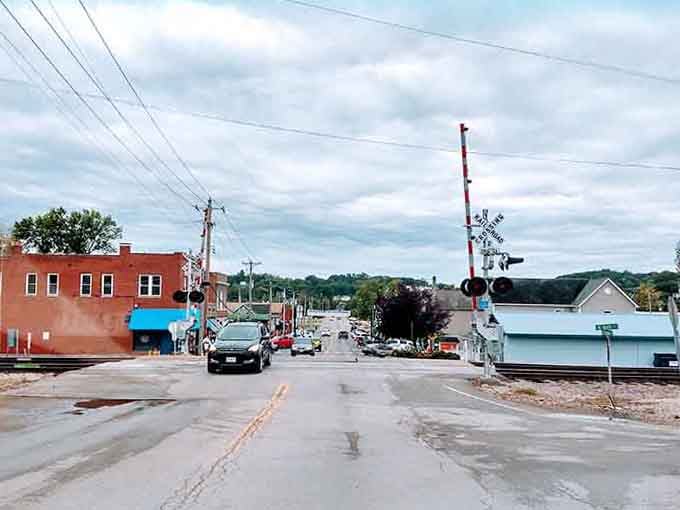 Railroad crossing signals guard this quiet street where trains still rumble through, connecting past and present with steel rails.