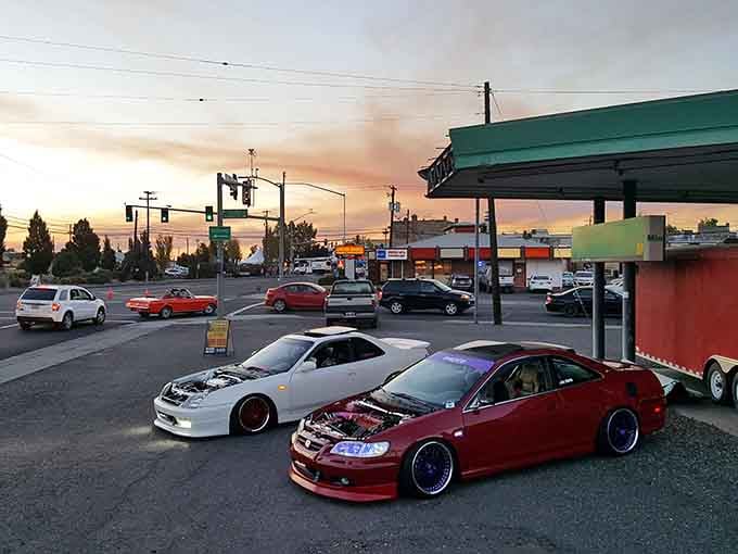 Sunset paints the sky in peach and coral while custom cars gather, proving entertainment here comes from community, not expensive venues.