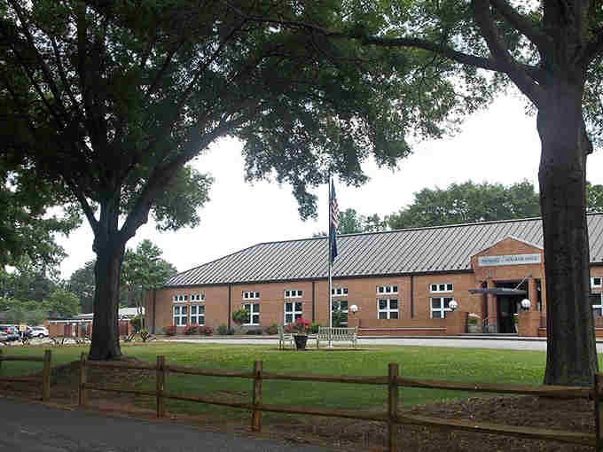 Massive shade trees frame this community center where metal roofing and brick walls blend tradition with practical Virginia sensibility.