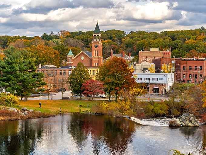 The autumn view across the river captures Putnam's church steeples and historic downtown reflected in peaceful waters below the hillside.