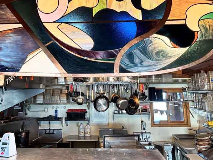 That colorful fish art above the kitchen adds whimsy to the workspace where sustainable magic happens daily with fresh ingredients.