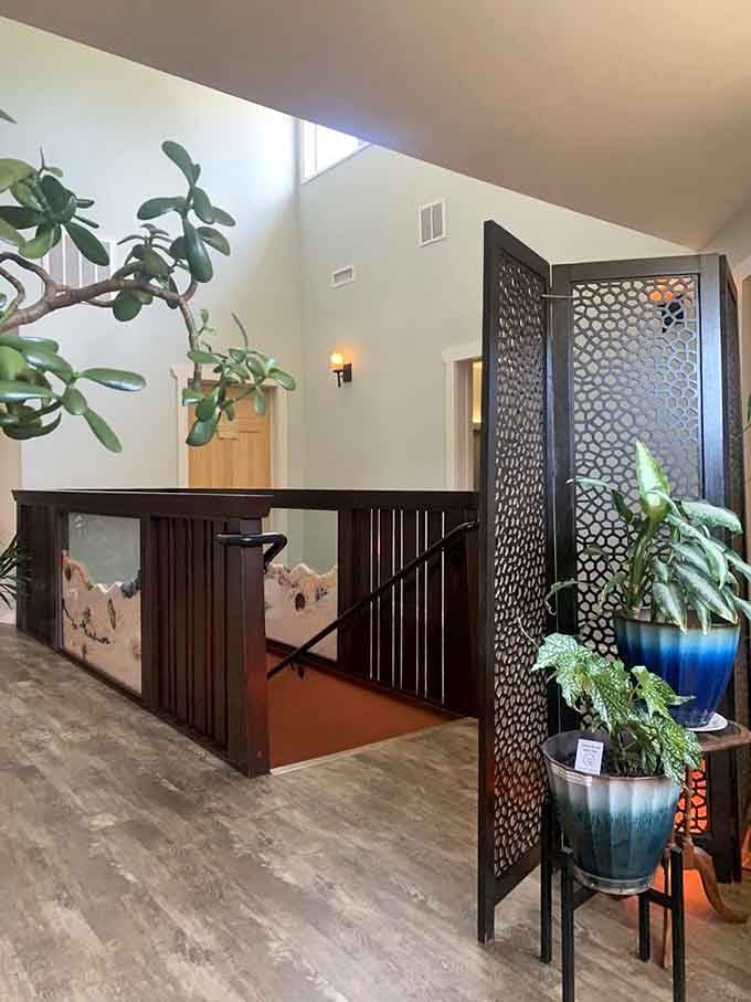 The welcoming upper hallway features decorative screens and plants, setting a tranquil tone before you descend.