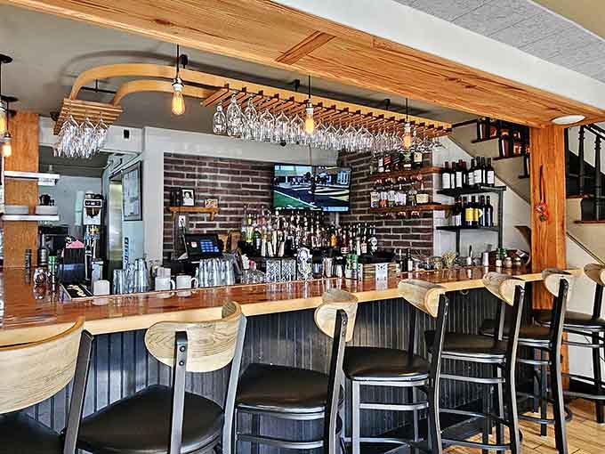 That bar area with wine glasses hanging overhead whispers "stay awhile" in the most inviting way.